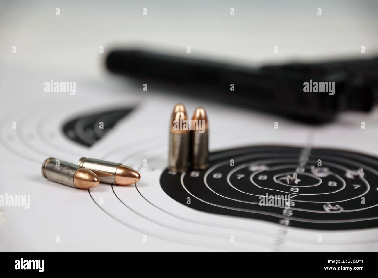Gun and many bullets shooting targets on white table in shooting range ...