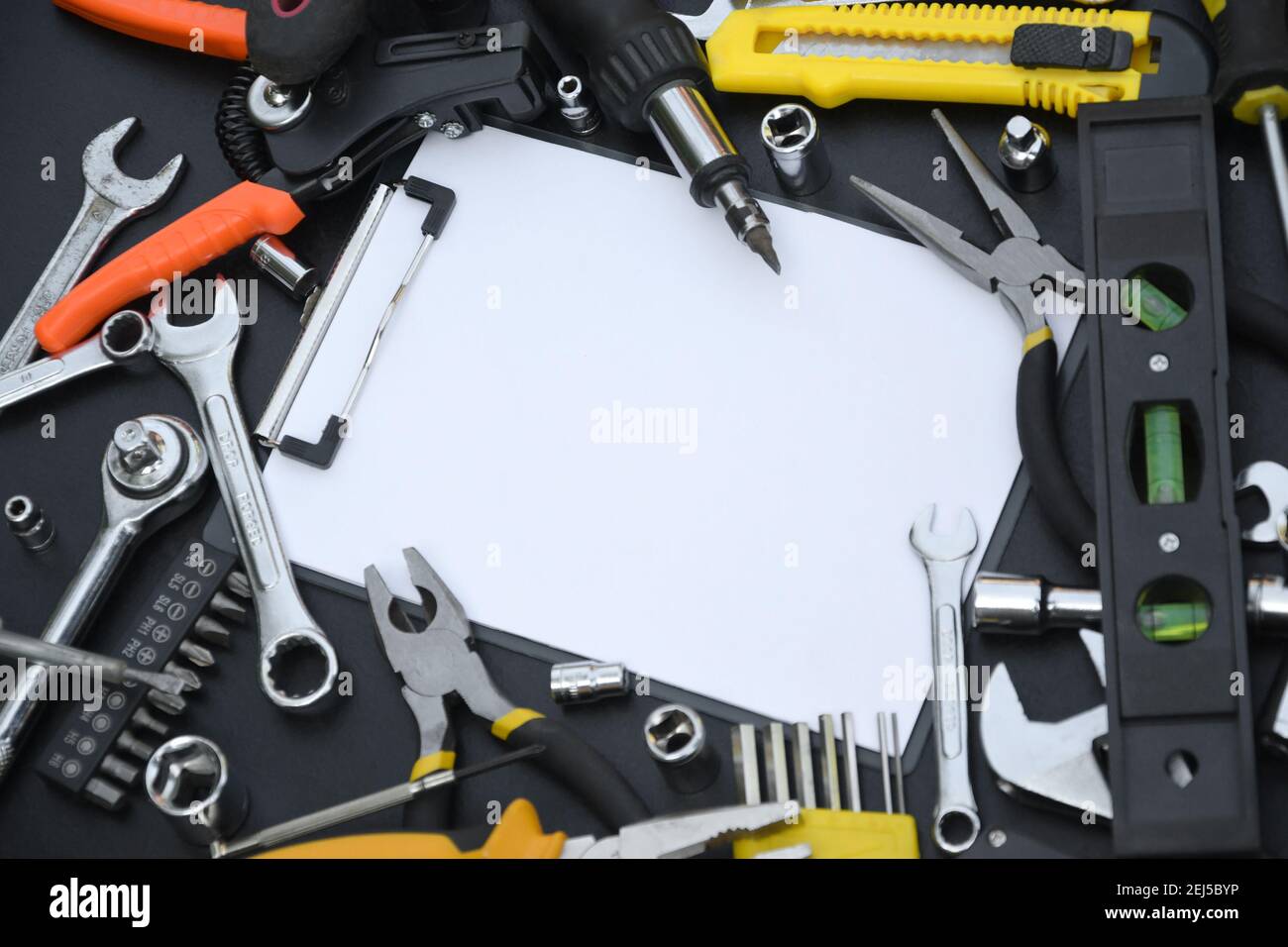 Handyman tool kit on black wooden table with copy space in blank paper ...