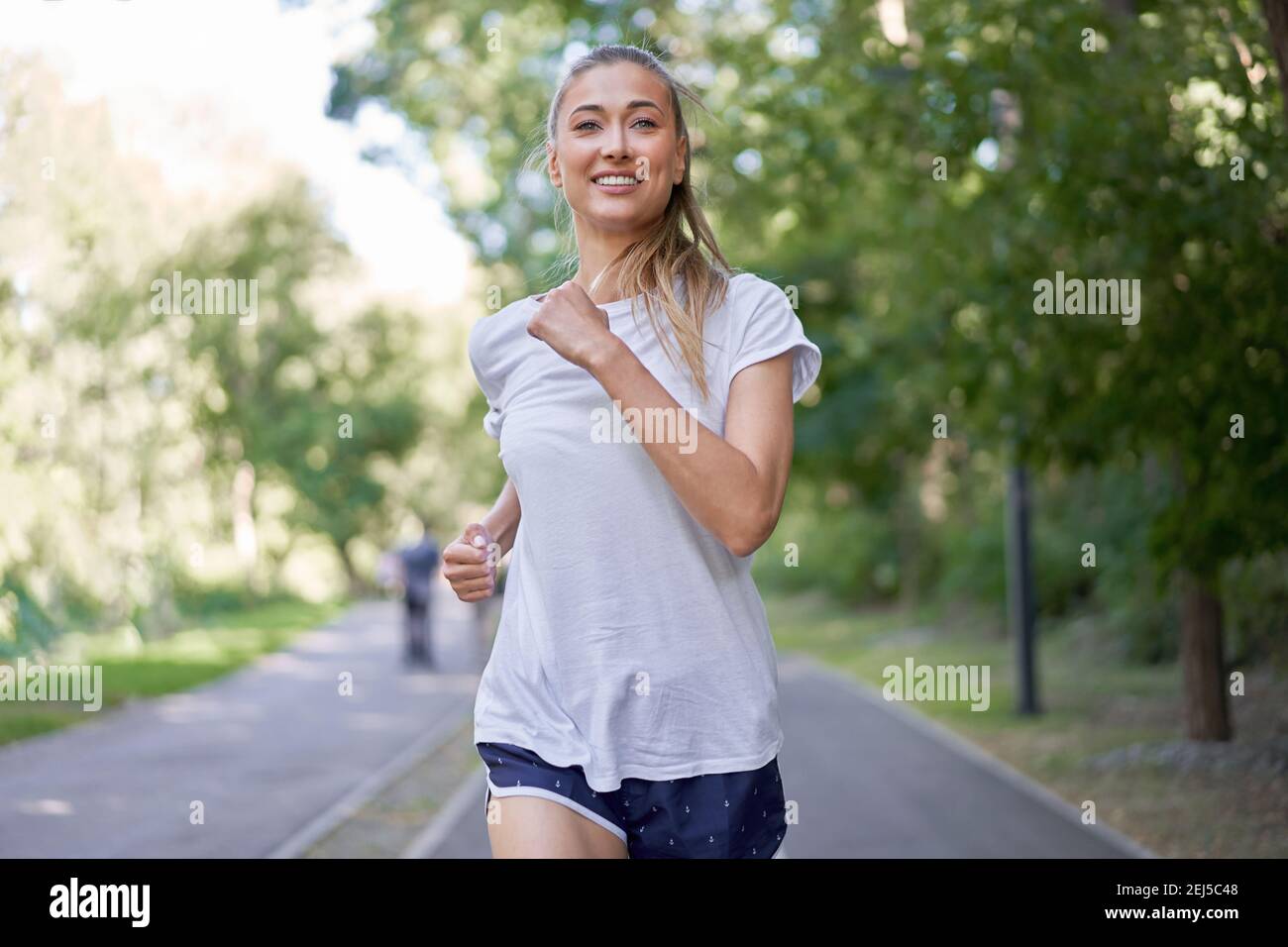 Woman running asphalt road summer park Active sporty caucasian female ...