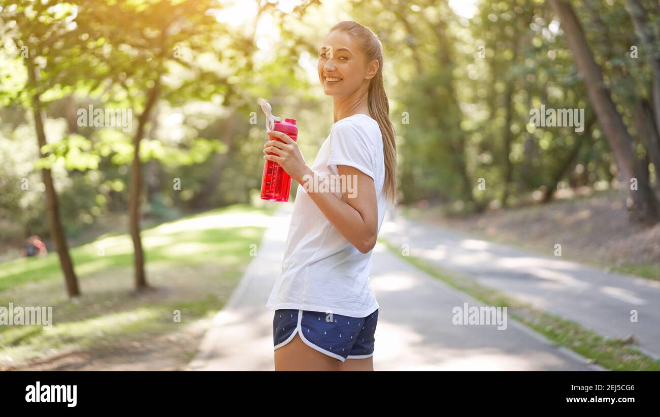 Woman drink water red bottle after morning workout. Young athletic ...