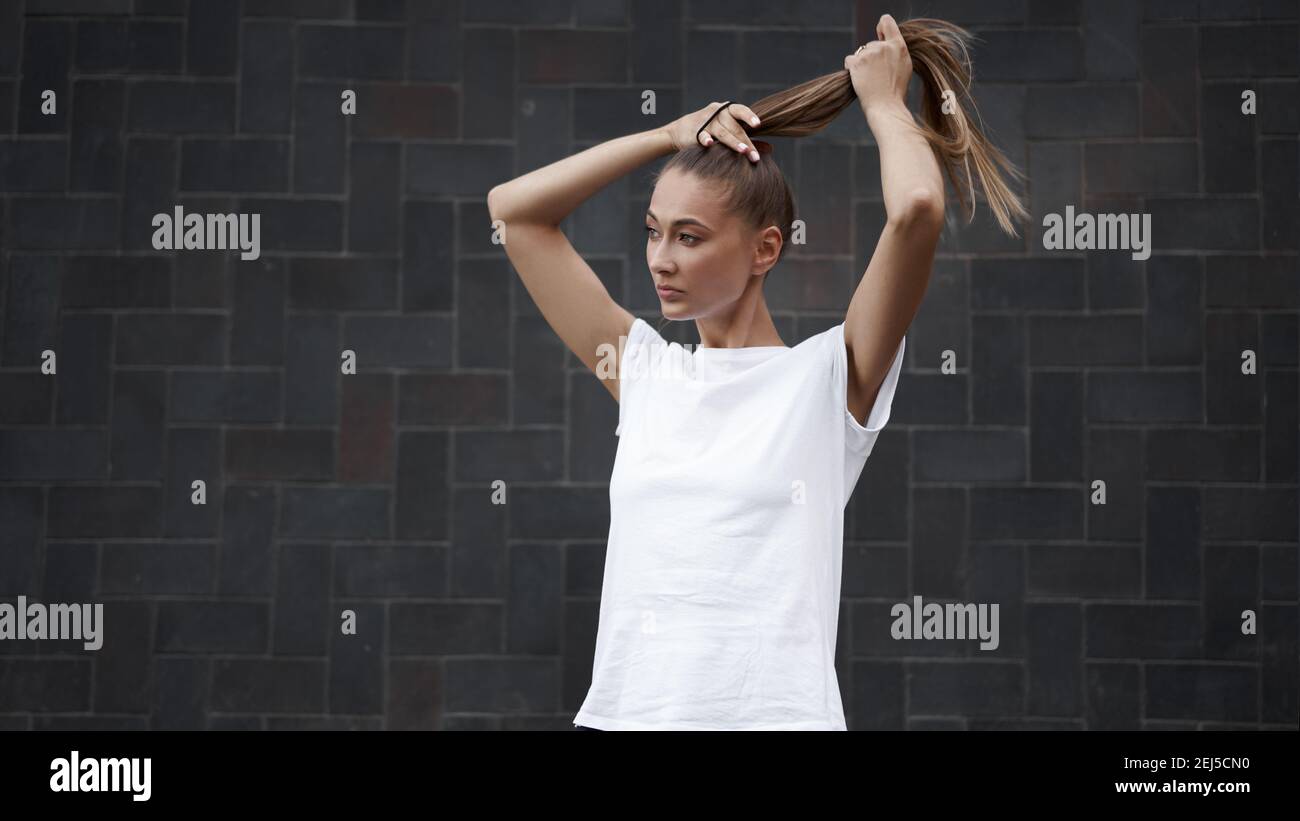 Woman Ties her hair in a ponytail before morning workout black wall ...