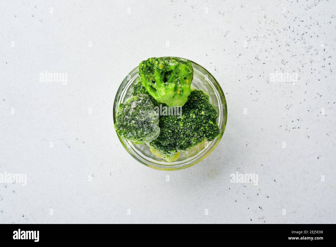 Frozen vegetables green broccoli in glass bowls on ice and concrete ...