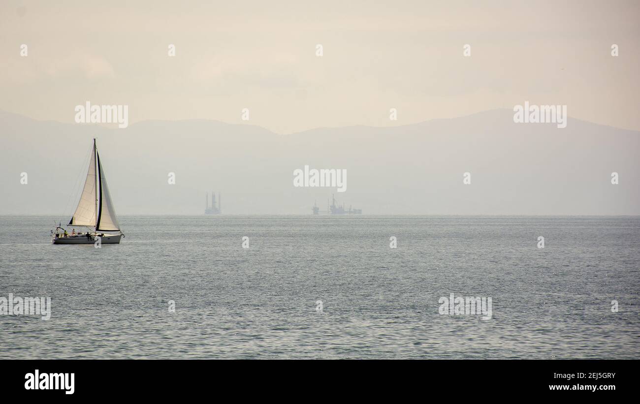 A closeup shot of a boat sailing in the calm sea with hills in the ...