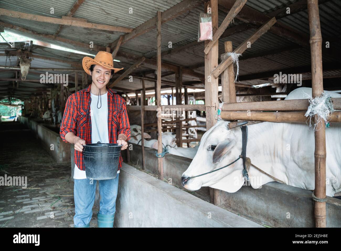 smiling man wearing casual clothes and hats while carrying buckets with ...