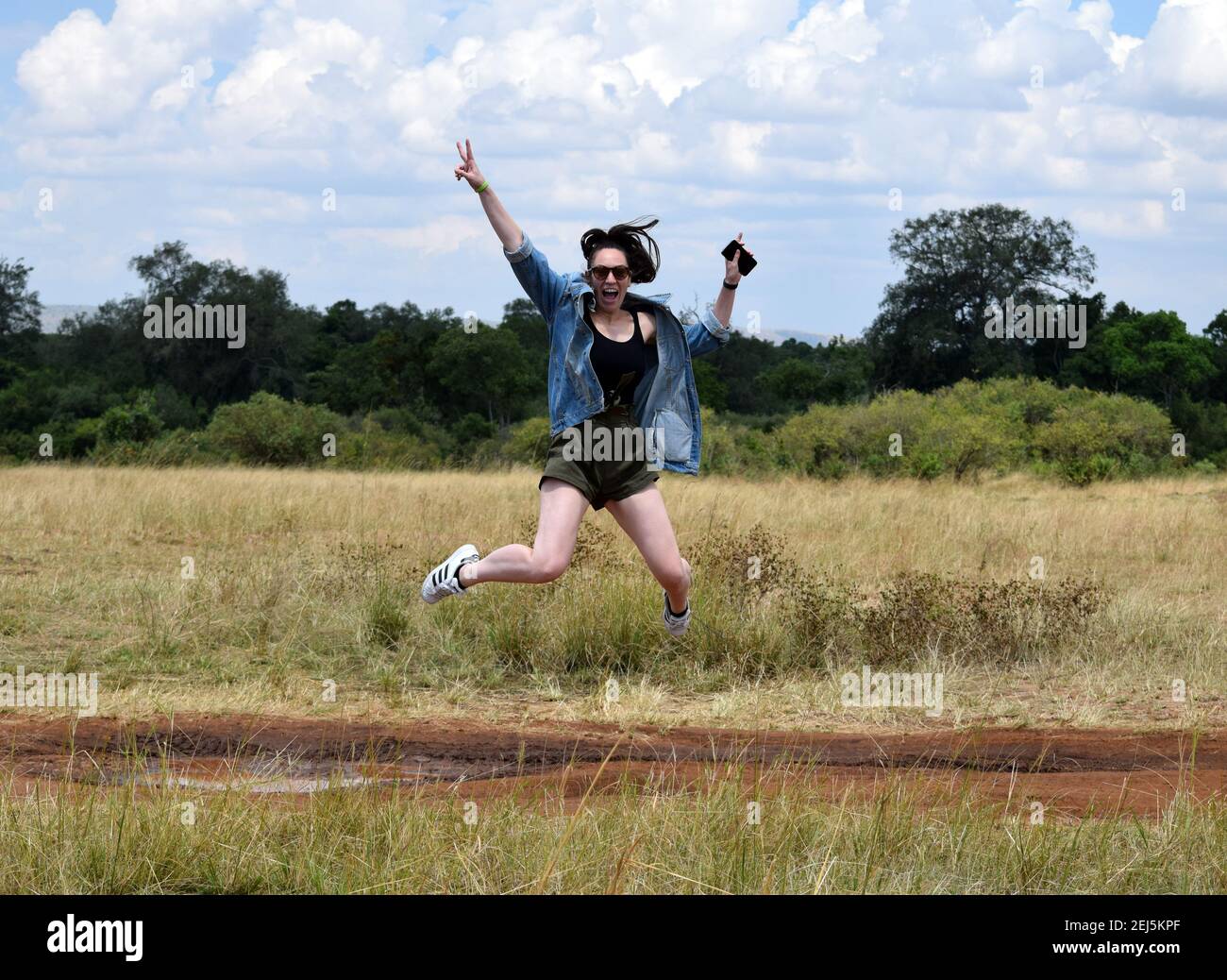 Happy girl jumping in Masai Mara National Park in Kenya Stock Photo - Alamy