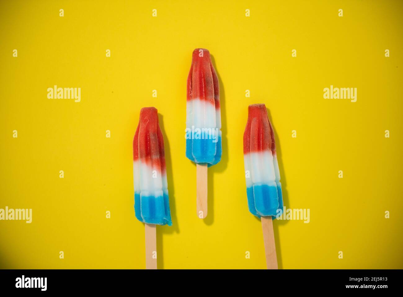 Three red, white and blue novelty ice cream bombpops shot on yellow ...