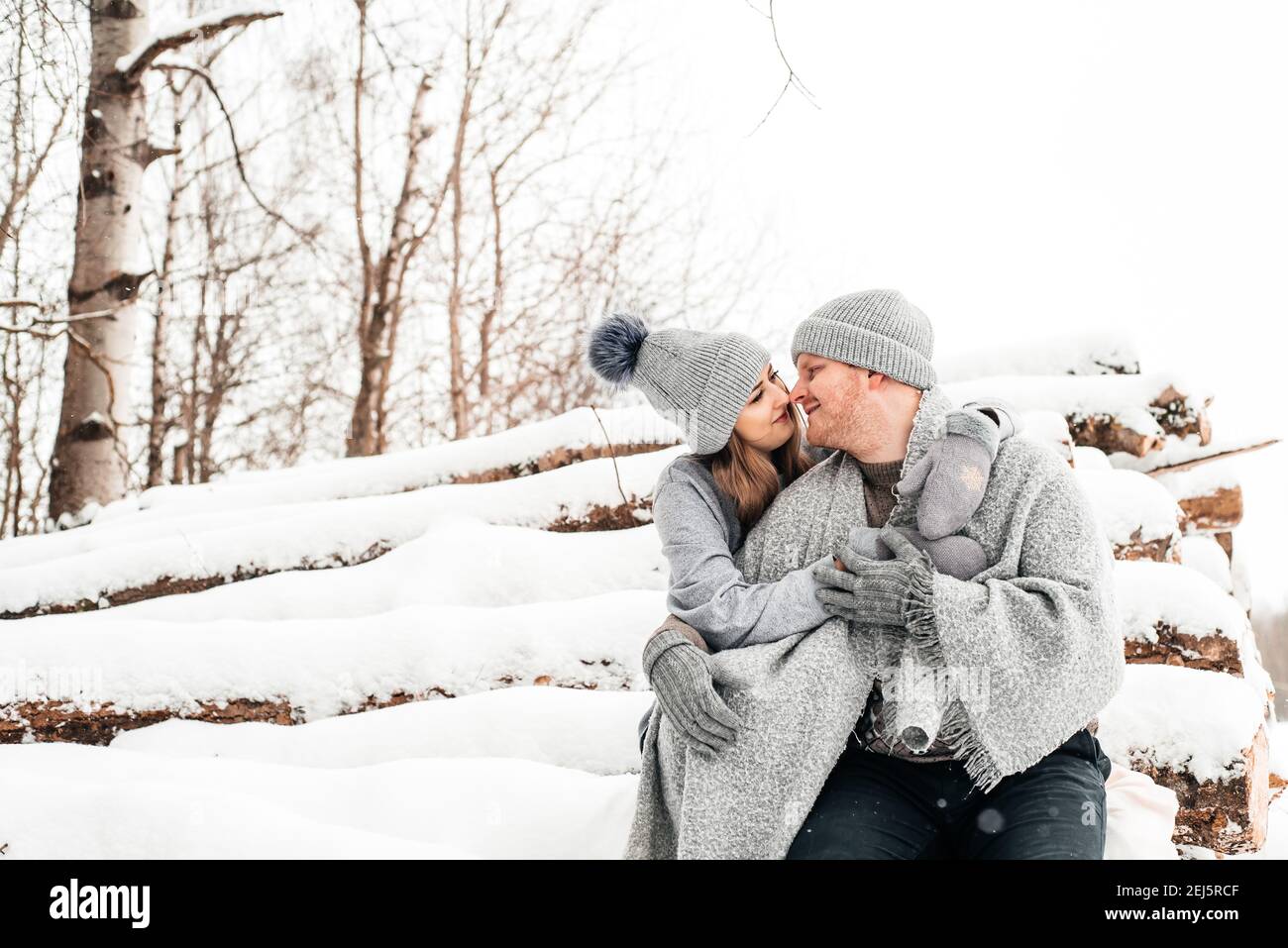 Cute couple in love sitting on the log, winter forest. Artwork Stock ...