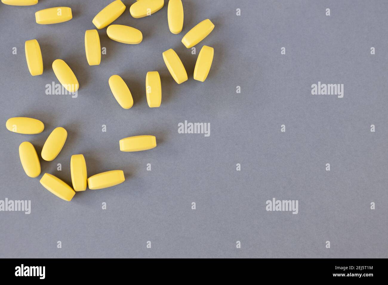 Yellow long vitamins or pills on a gray background, close-up, mock up ...