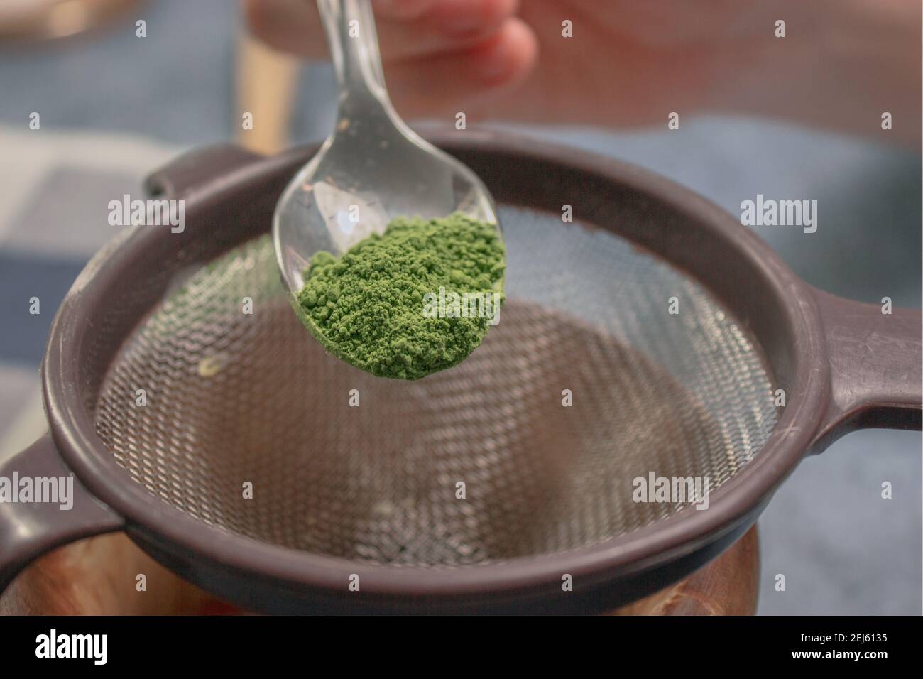 Vertical image matcha tea powder with strainer to sprinkle in a wooden ...