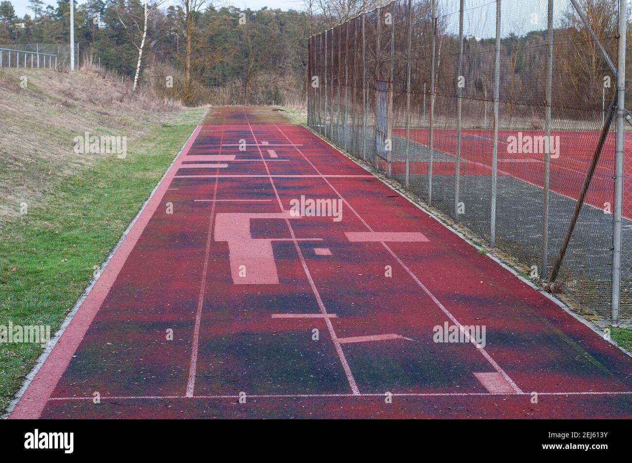 a red rubber running track at an empty sports area with a high chain ...