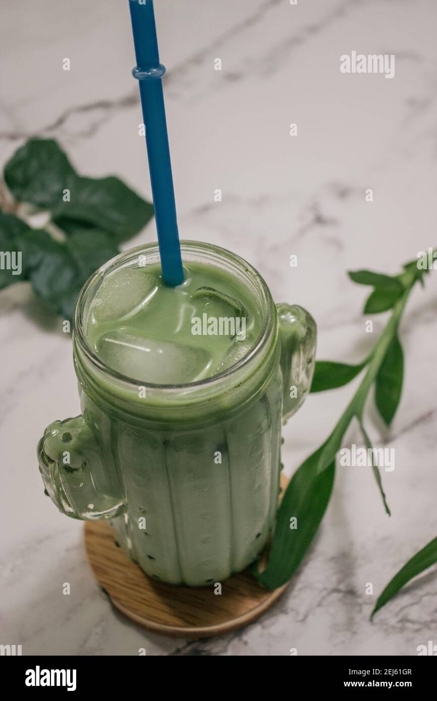 Close up vertical image Iced Matcha Tea on white marble background with ...