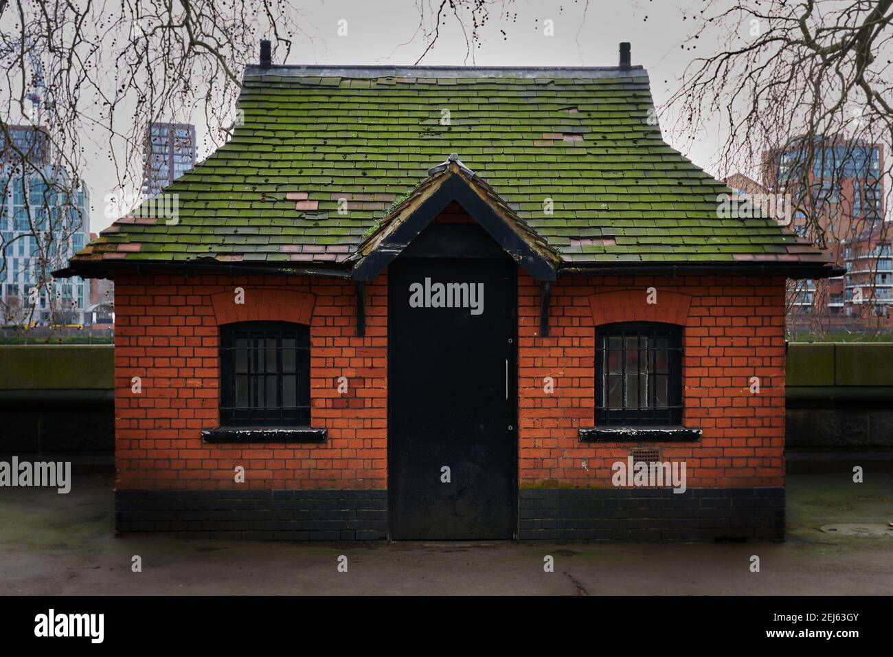 Small 1 story brick building with one black door, two windows and slate ...