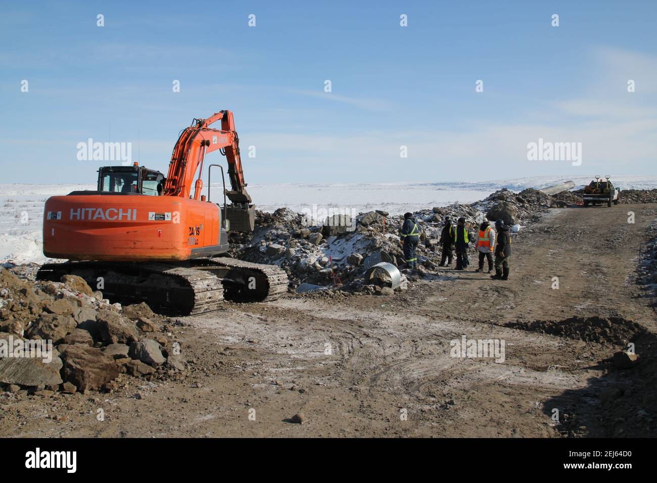Hitachi Excavator and workers installing culvert during winter ...