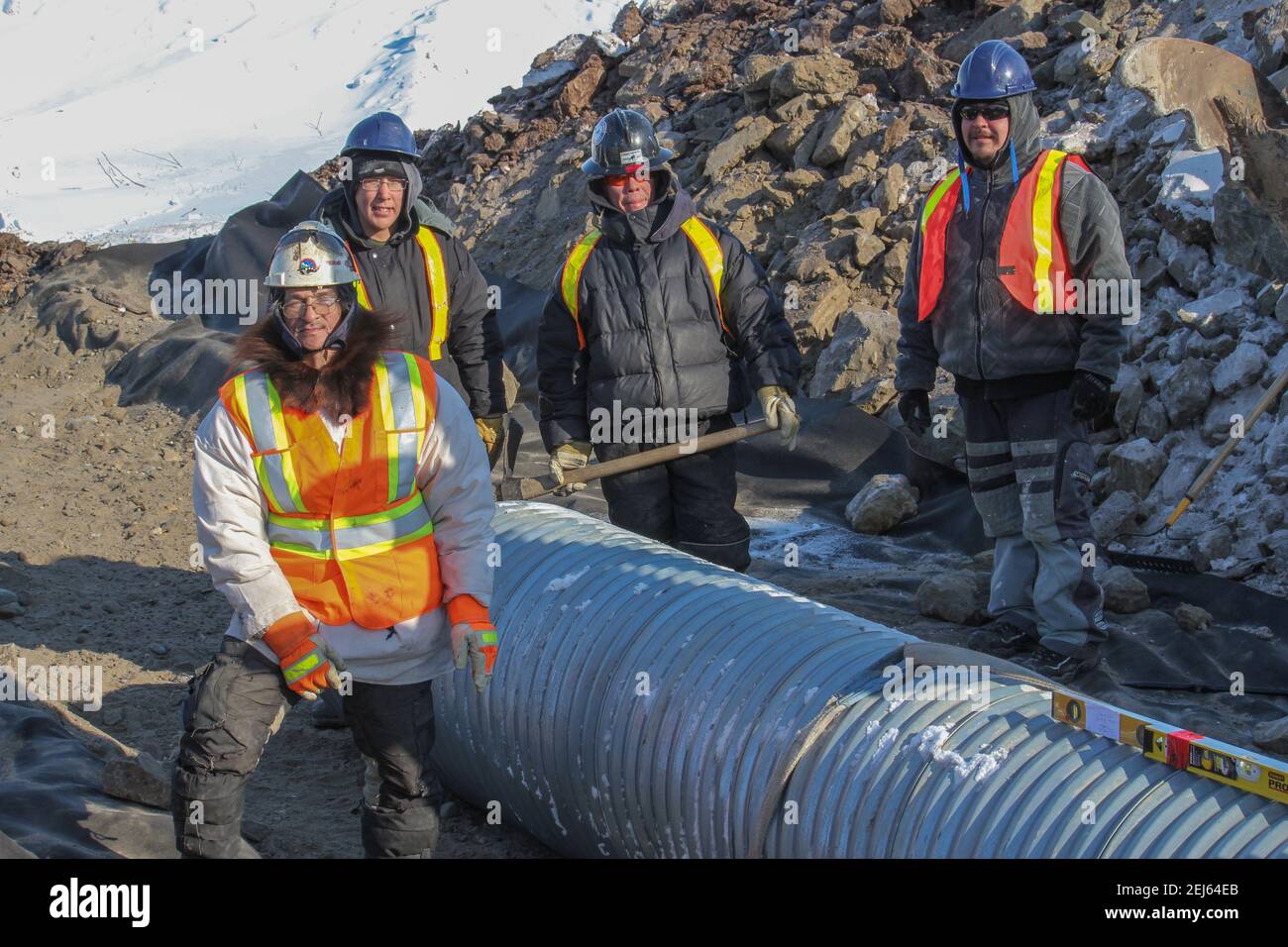 Four Indigenous male workers installing culvert during winter ...