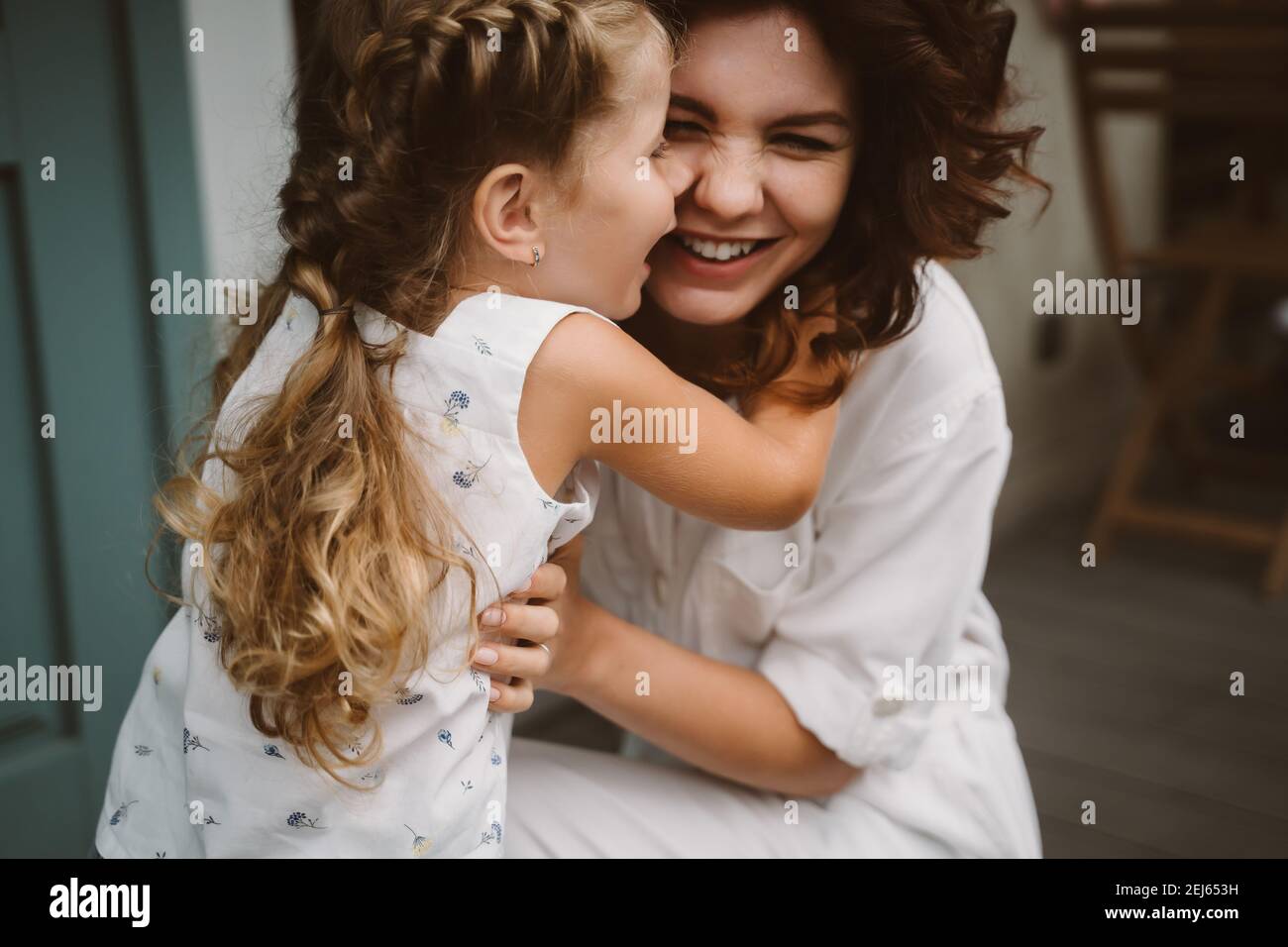 Cute little girl and her beautiful young mom hug each other Stock Photo - Alamy