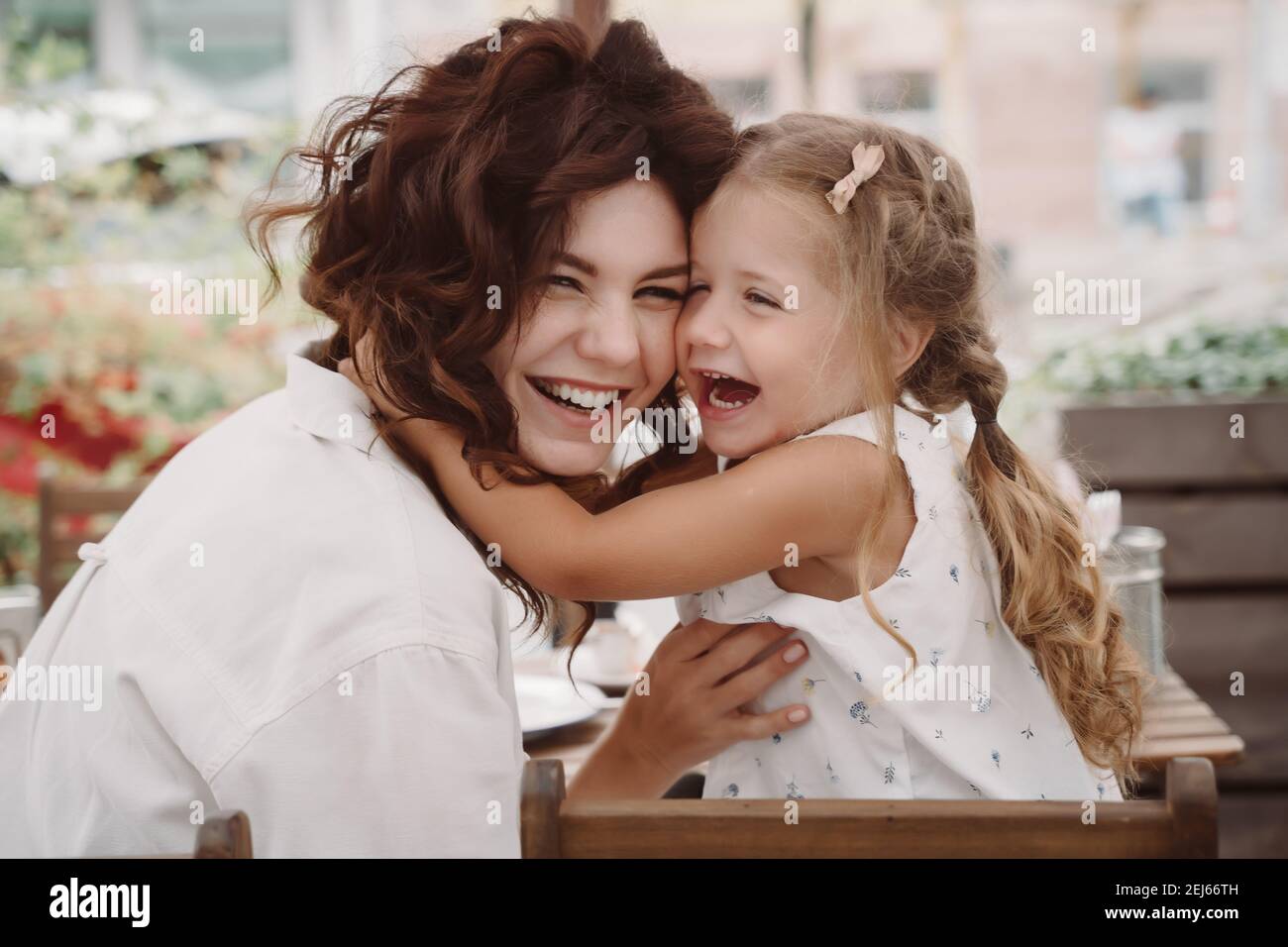 Cute little girl and her beautiful young mom hug each other Stock Photo - Alamy