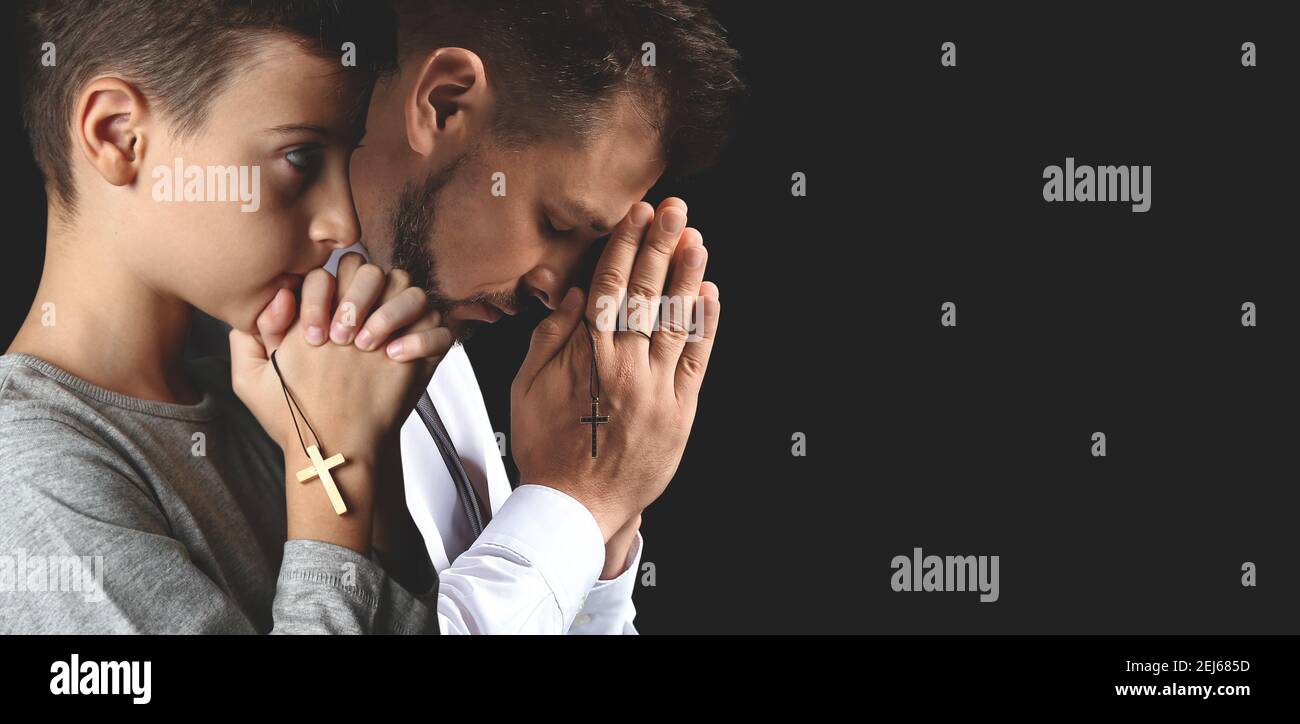 Religious man and boy praying to God on dark background Stock Photo - Alamy