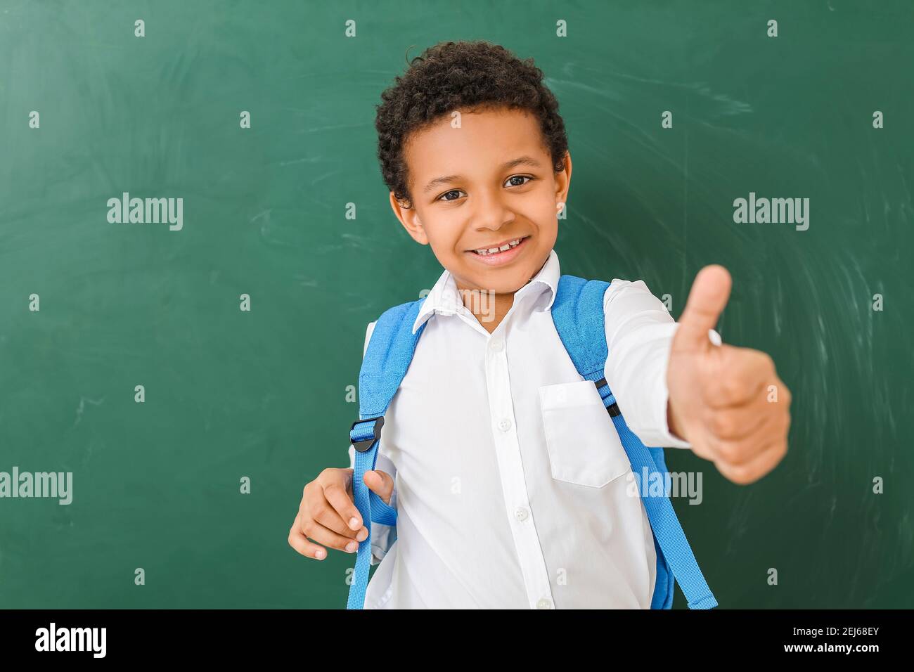 Little African-American schoolboy showing thumb-up gesture near ...