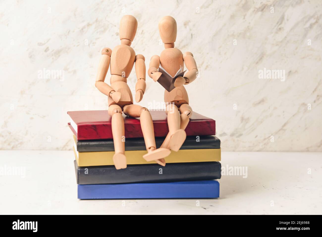 Wooden mannequins with books on light background Stock Photo - Alamy