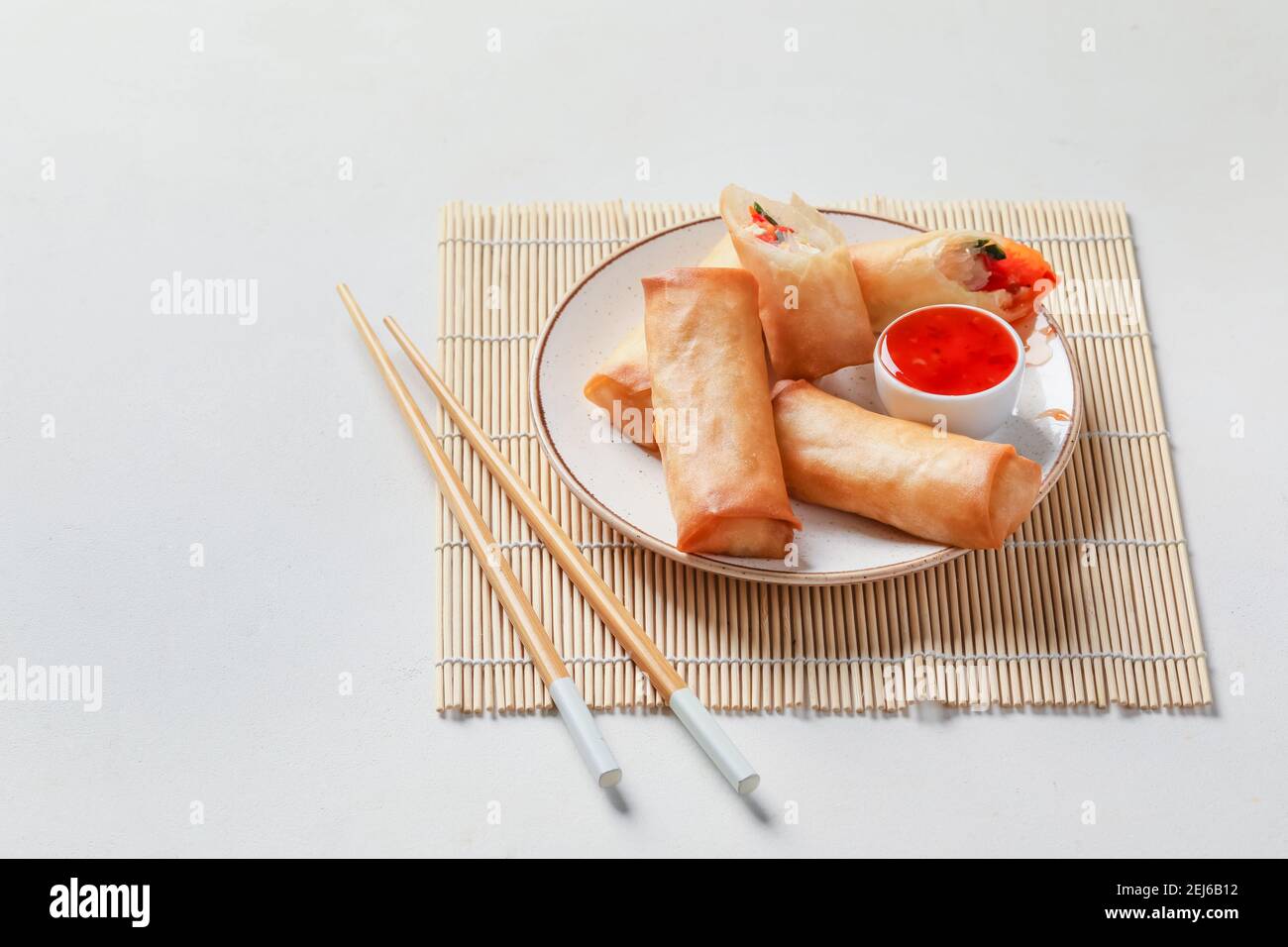Plate with tasty fried spring rolls and sauce on light background Stock ...