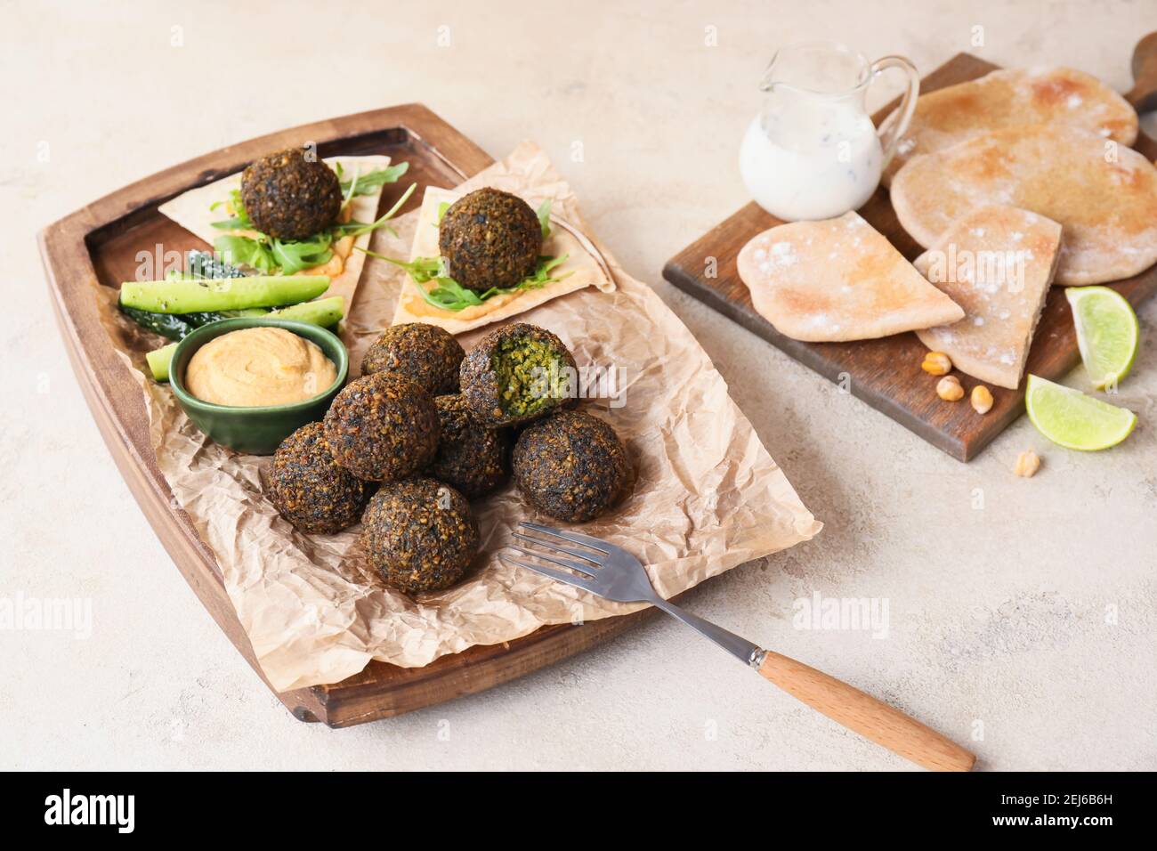 Board with tasty falafel balls, pita and sauce on light background ...