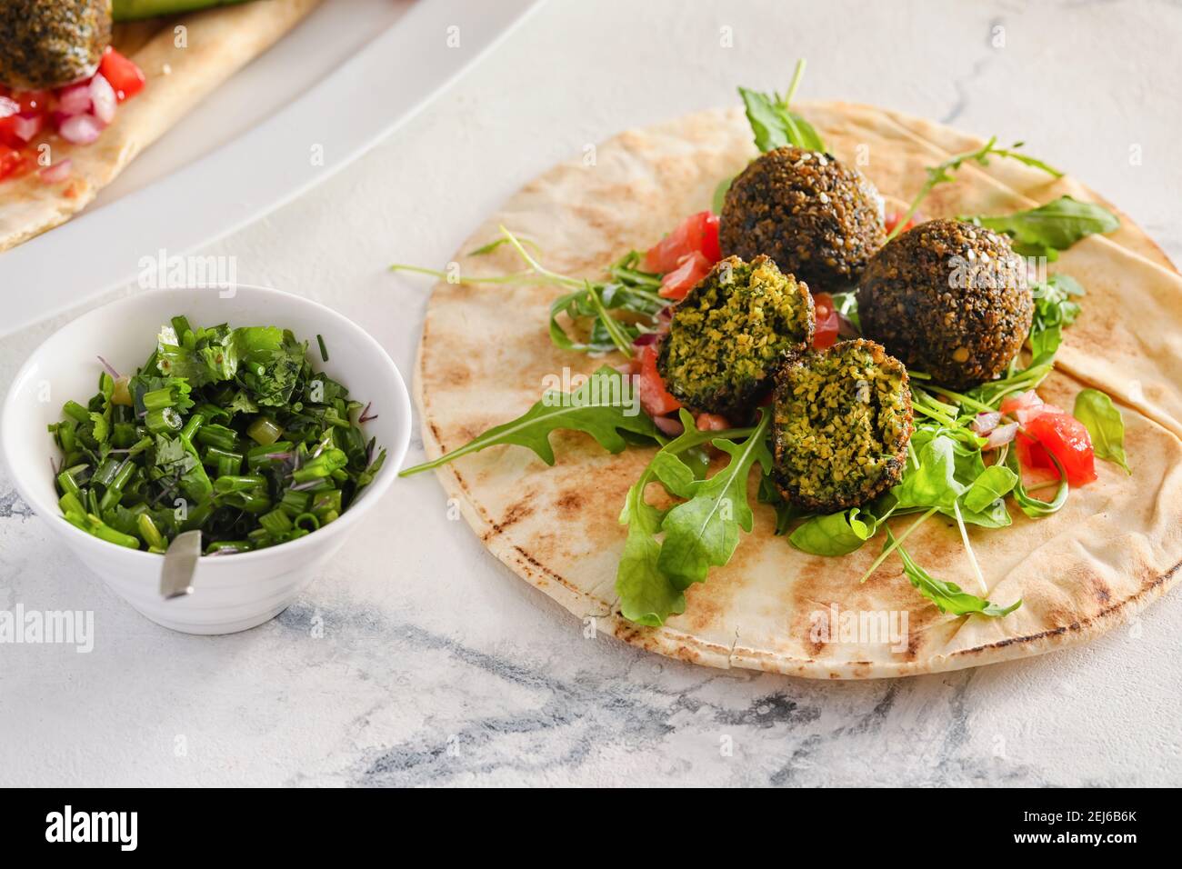 Board with tasty falafel balls, pita and vegetables on light background ...