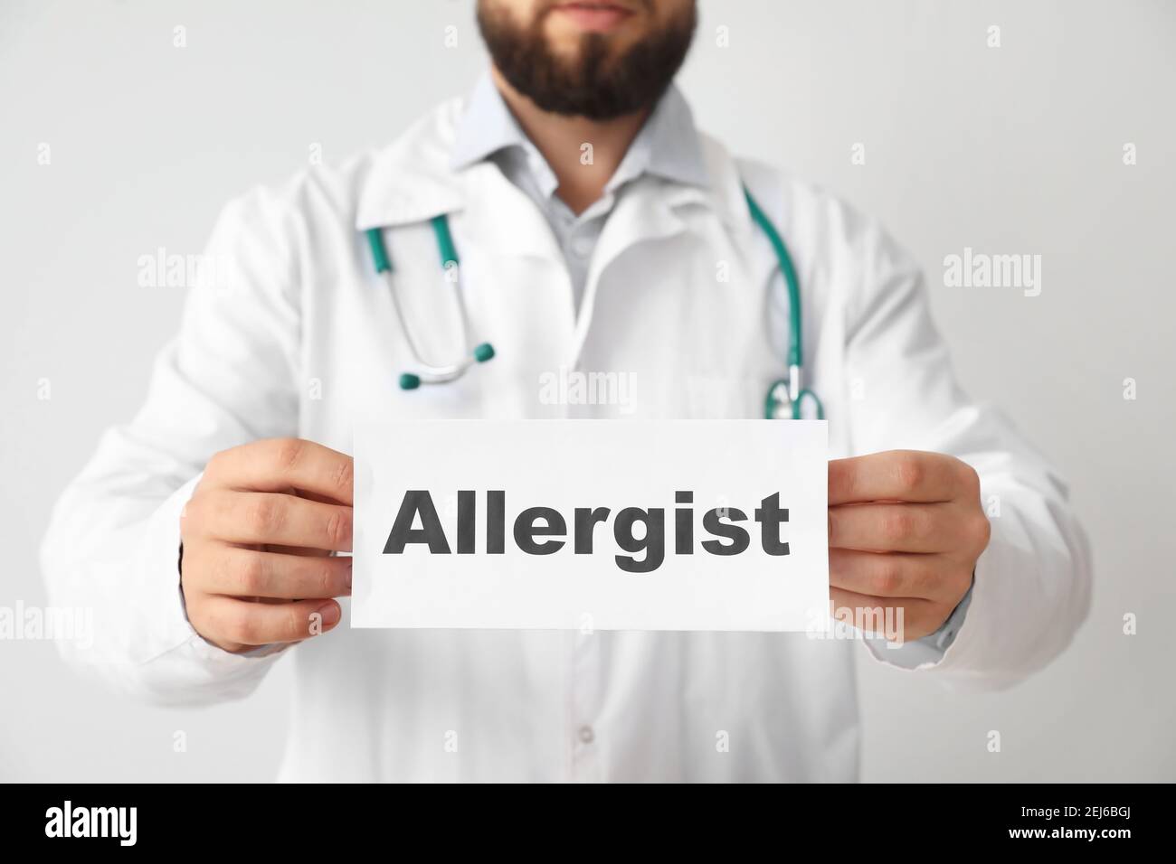 Doctor holding paper with word ALLERGIST on light background Stock ...