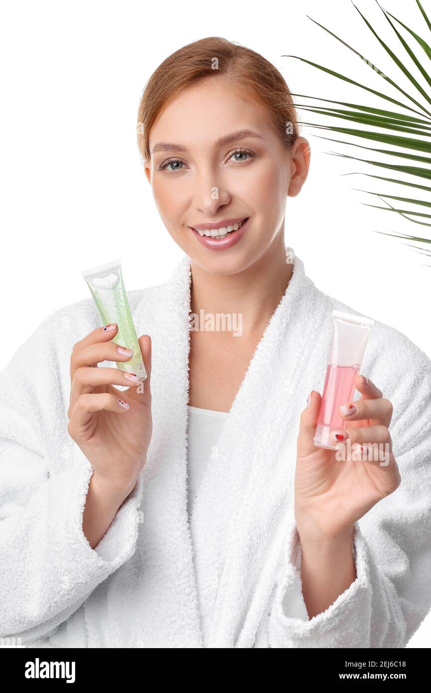 Beautiful young woman with cosmetic products and tropical leaf on white ...