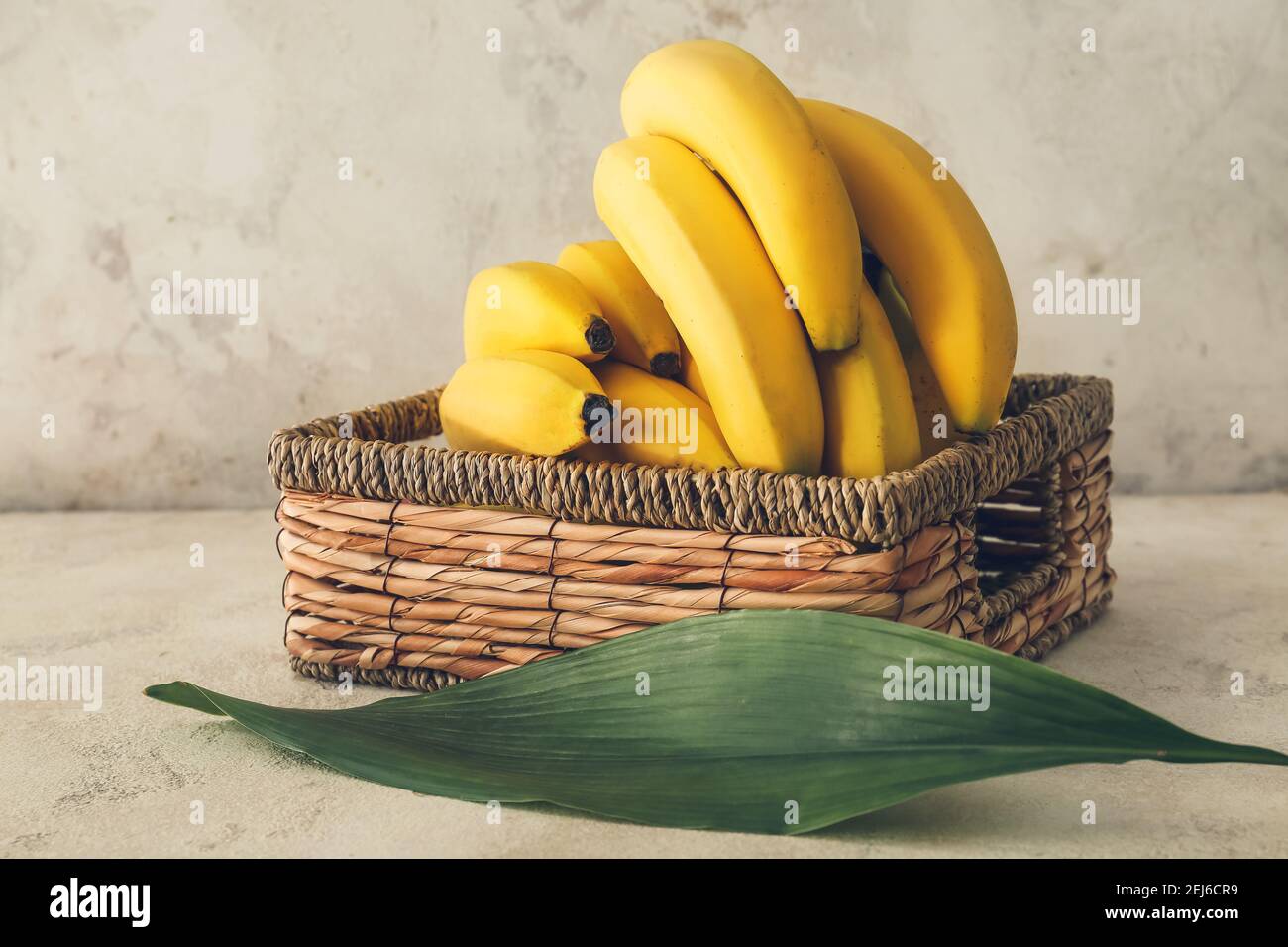 Wicker basket with ripe bananas on dark background Stock Photo - Alamy