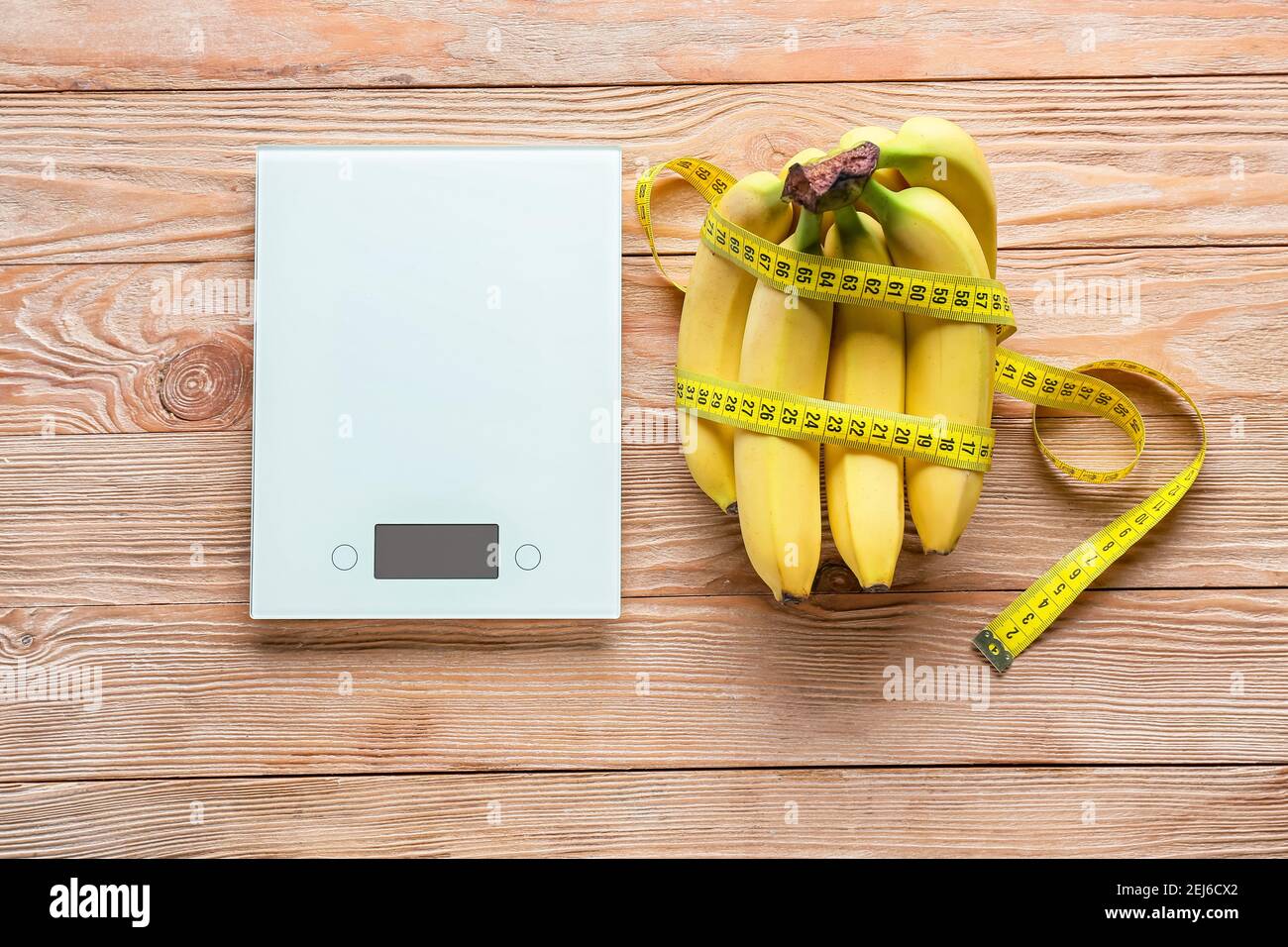 Ripe bananas, measuring tape and scales on wooden background. Weight ...