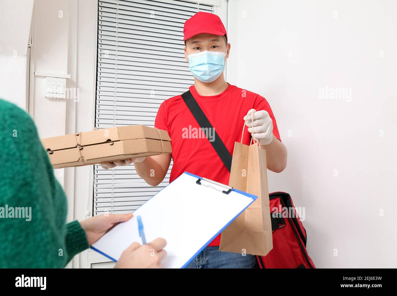 Woman receiving her order from courier of food delivery service Stock ...