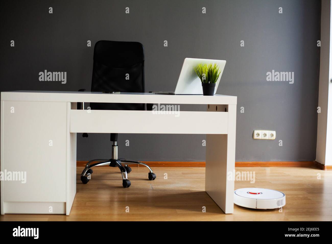 Smart House. Vacuum cleaner robot runs on wood floor in a office Stock ...