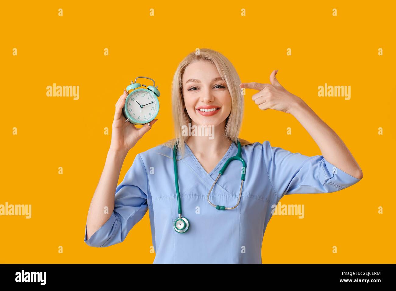 Female doctor with alarm clock on color background. Time to check your ...