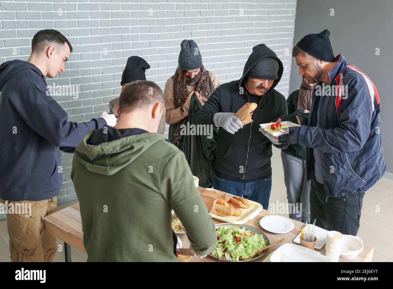 Volunteers giving food to homeless people in warming center Stock Photo ...