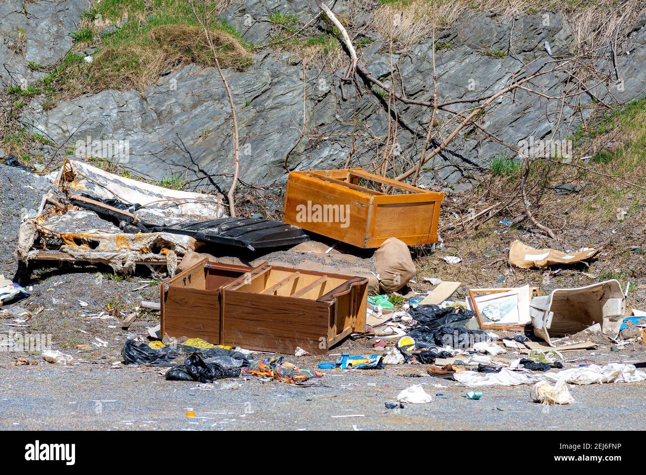 A collection of garbage at the bottom of a rock cliff. Included is ...