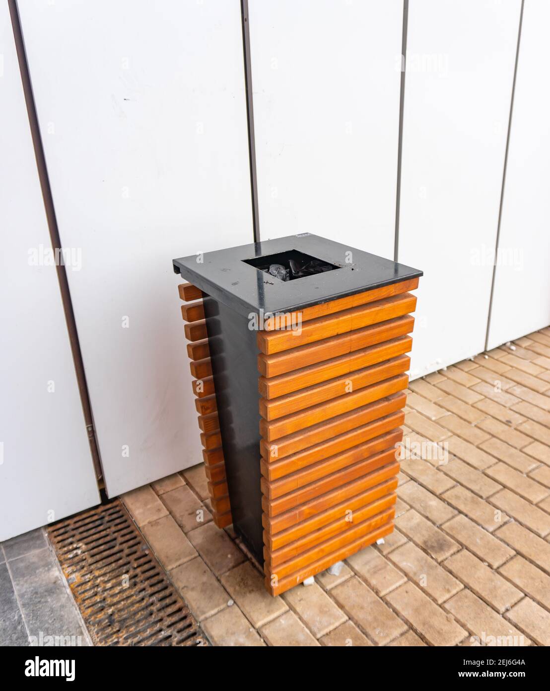 City trash can. Brown wooden trash can on a sidewalk near shopping ...