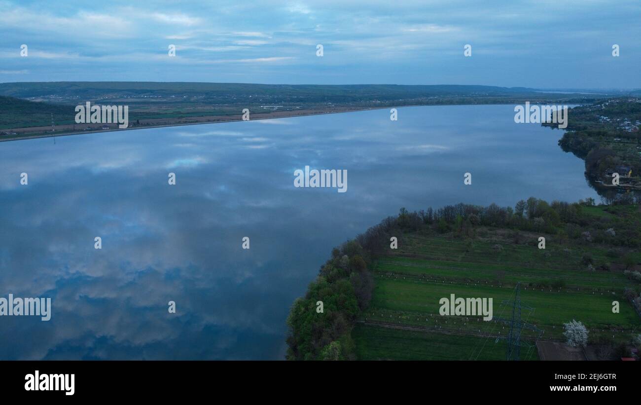Aerial view of a reflecting river with forests and buildings under the ...