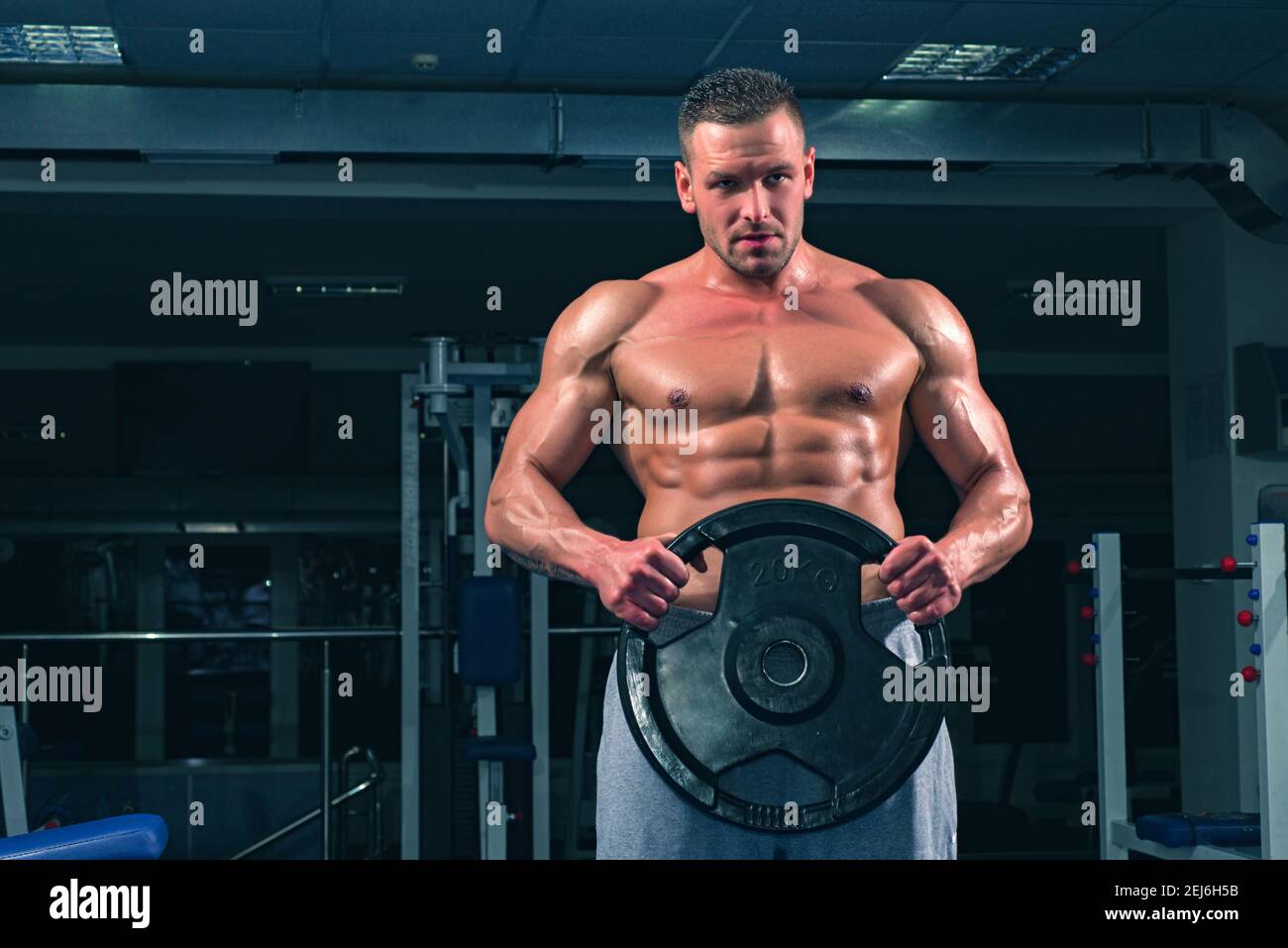 Powerlifter with weight disk in sport gym. Bodybuilder with heavy disk ...