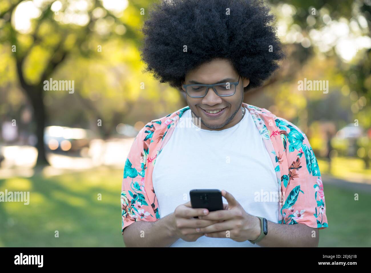 Latin man using his mobile phone outdoors Stock Photo - Alamy