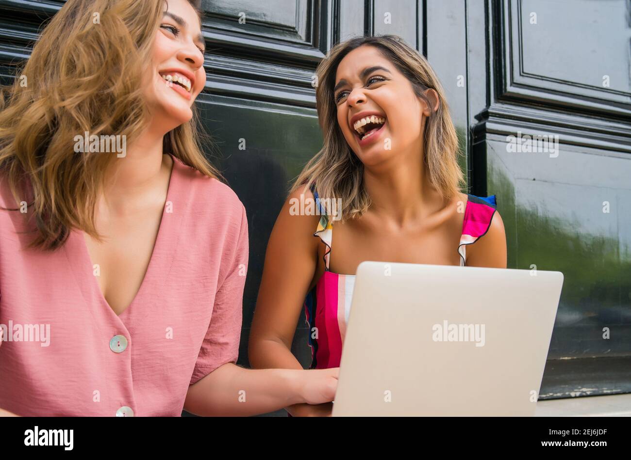 Two friends using laptop outdoors Stock Photo - Alamy