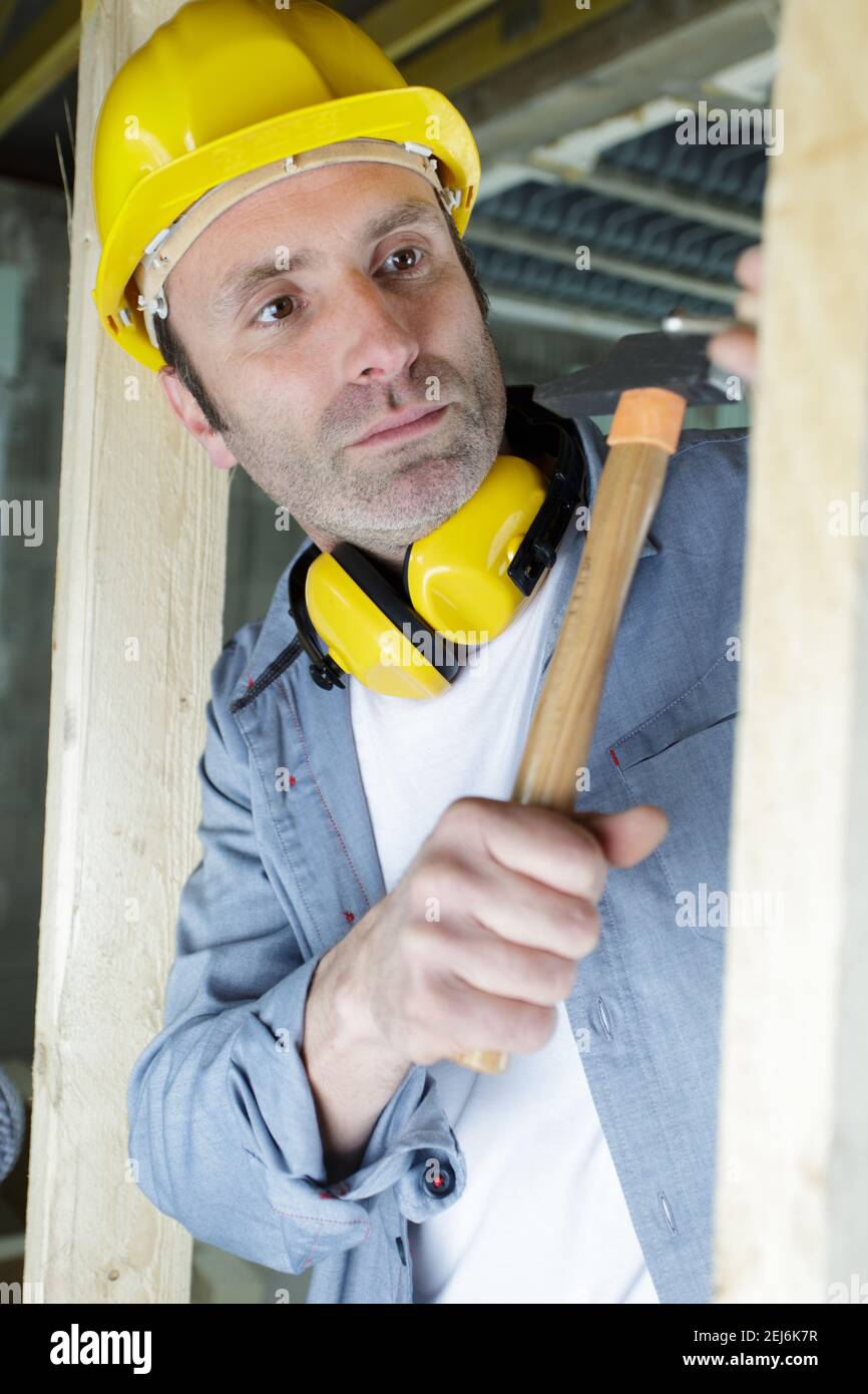 male builder hammers into the wall Stock Photo - Alamy