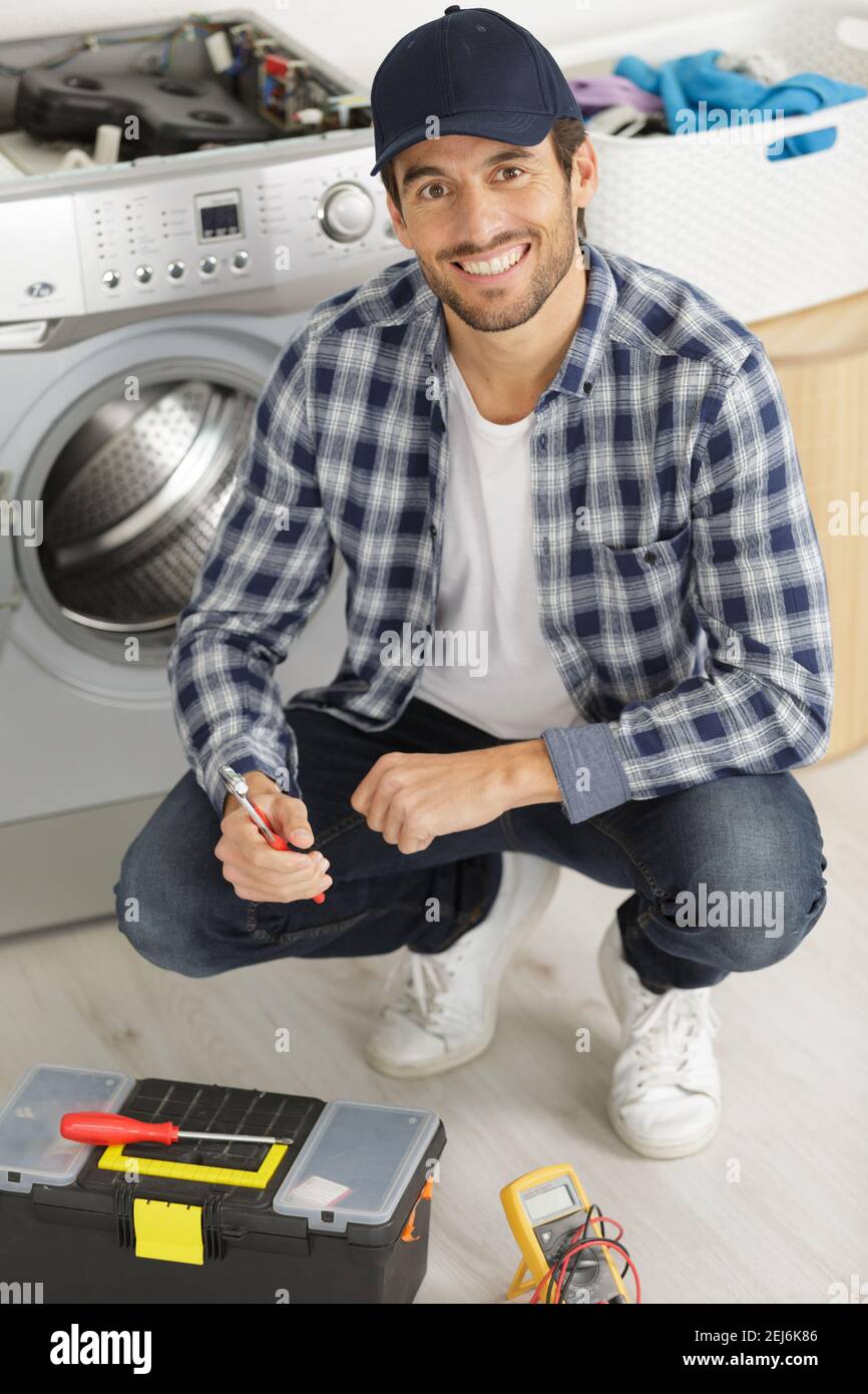 working man fixing a washing machine in laundry Stock Photo - Alamy