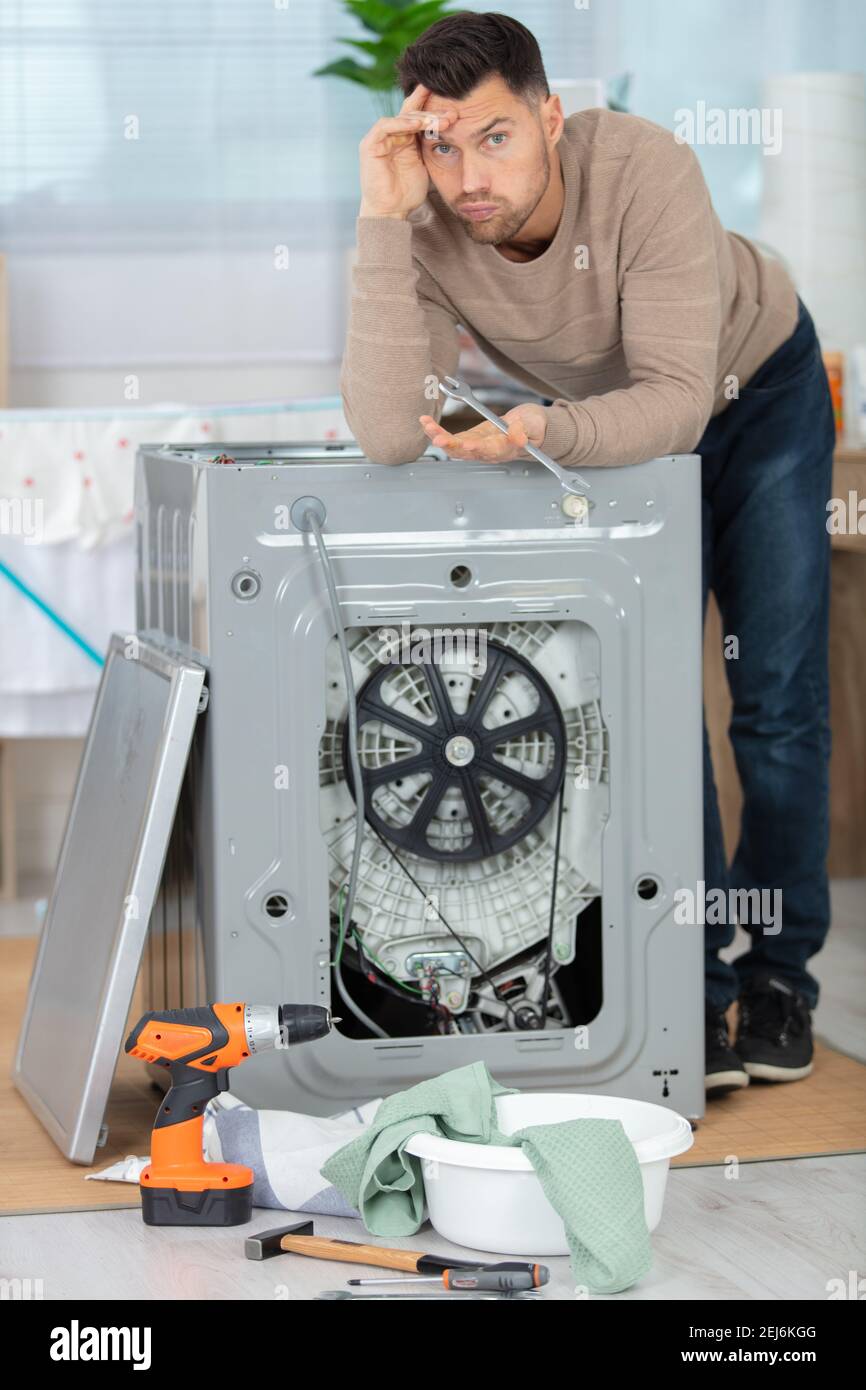 disappointer man repairing washing machine Stock Photo - Alamy