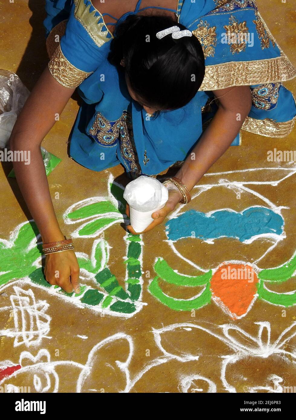 Indian Hindu woman draw traditional rangoli during harvest festival ...