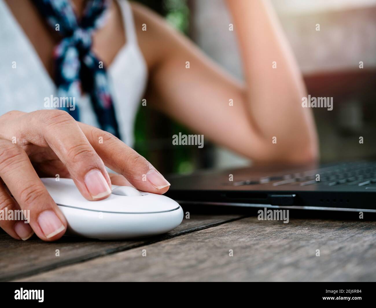 Close up finger using modern white wireless mouse while working on black laptop computer on ...