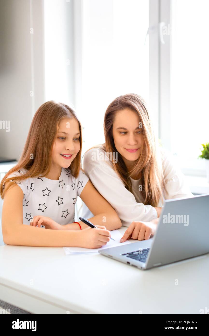 Online education concept. Mom helps her daughter do her homework online ...