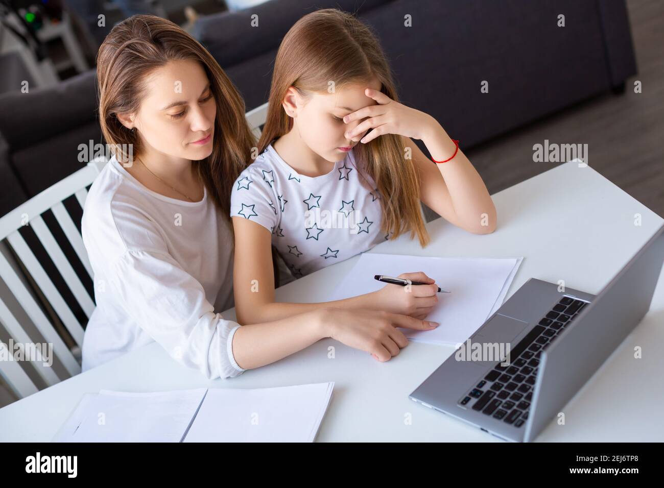 Sad student doing lessons online with mom. She covered her face in ...