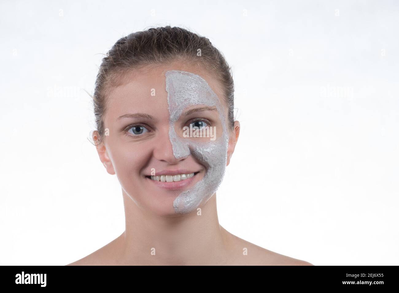 Cosmetic mask of gray clay with scrub on the face of a beautiful young ...