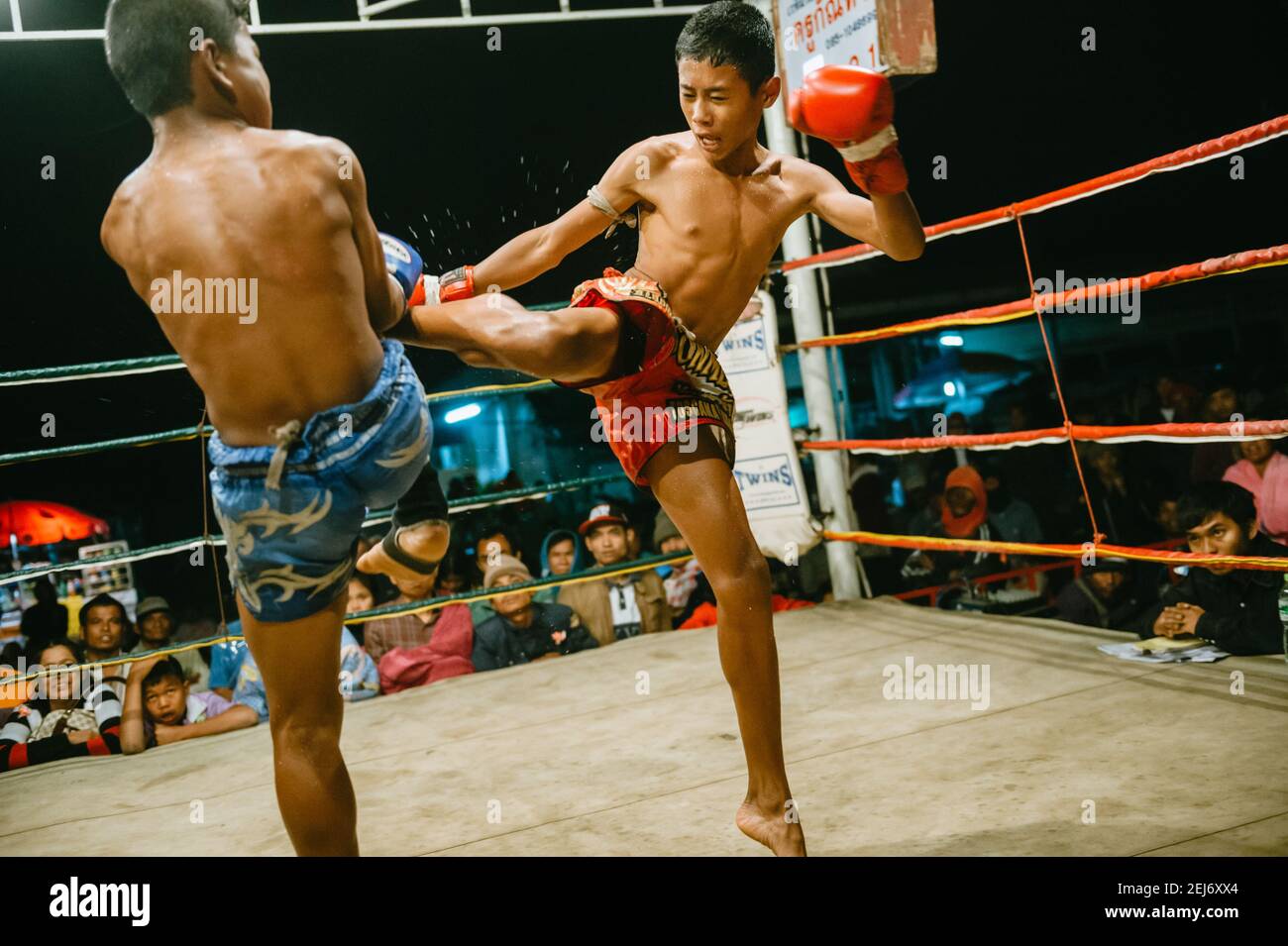 Thai boxing Muay Thai competition, one of the boxers throwing a high ...