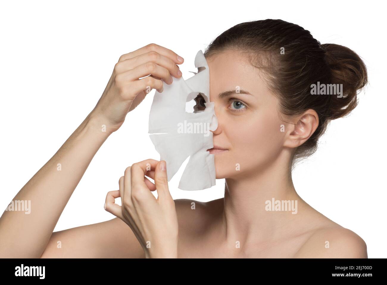 Beautiful young woman is applying a cosmetic tissue mask on a face on a ...